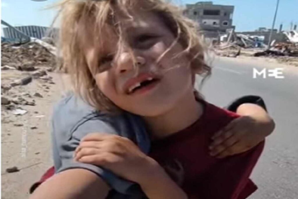 La bambina che a Gaza porta sulle spalle la sorellina ferita